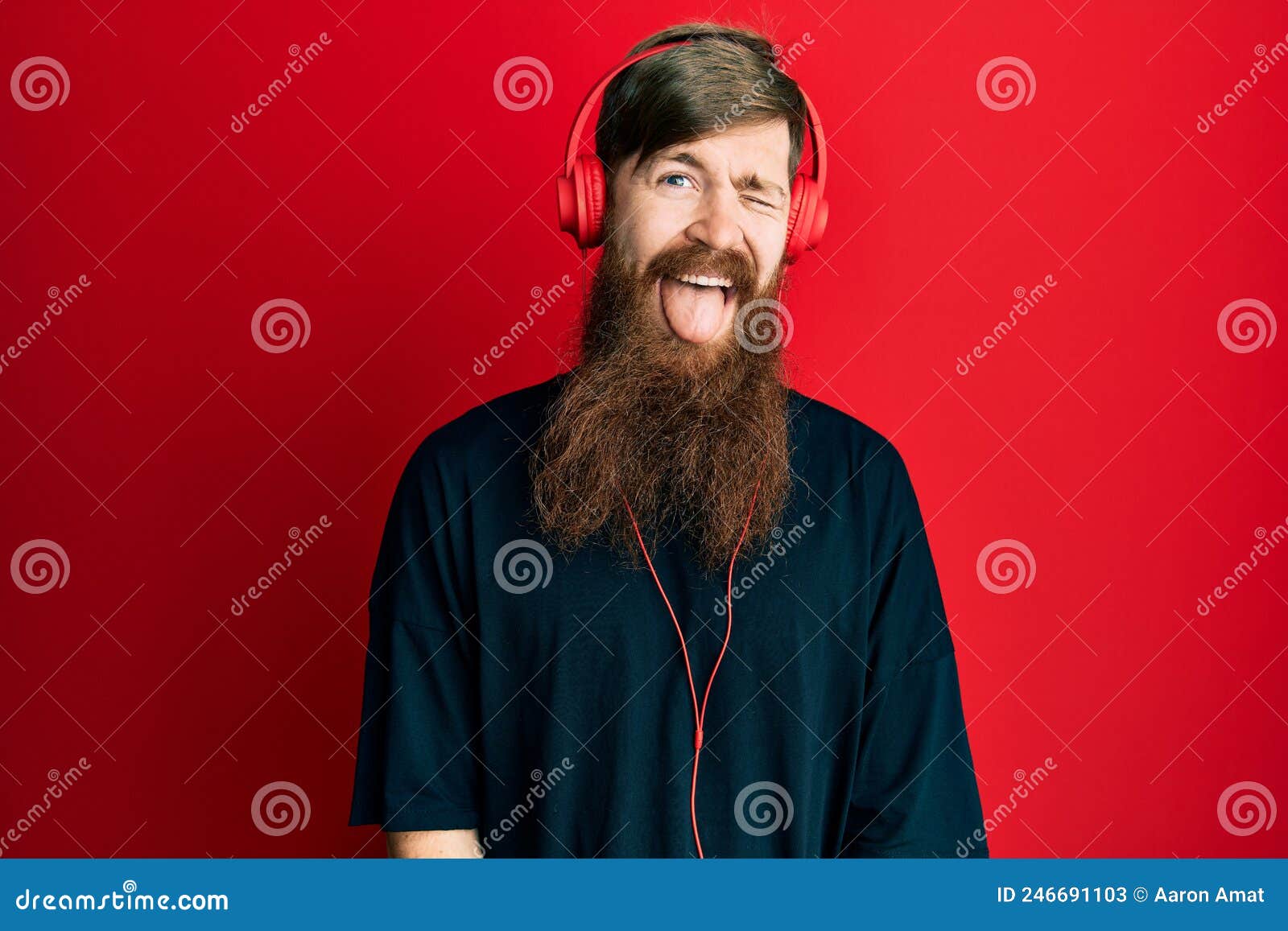 Redhead Man With Long Beard Listening To Music Using Headphones Winking