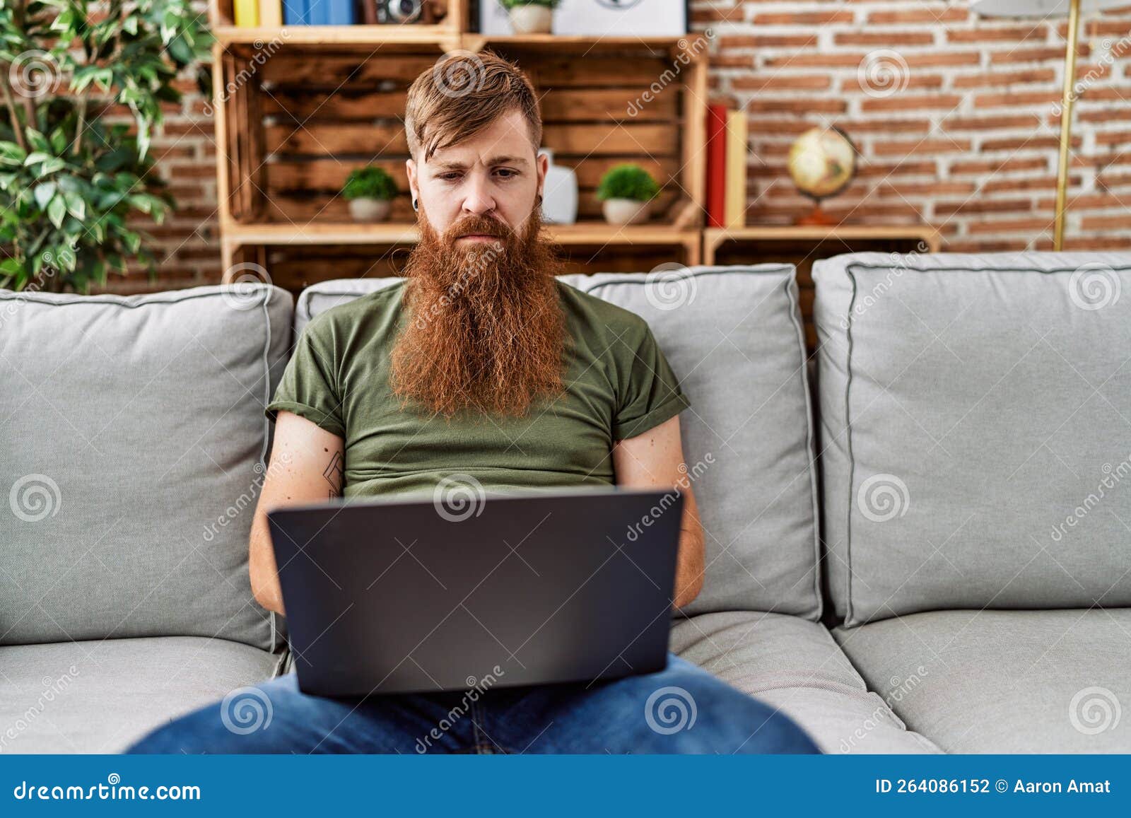 Redhead Man with Long Beard Using Laptop Sitting on the Sofa at the ...
