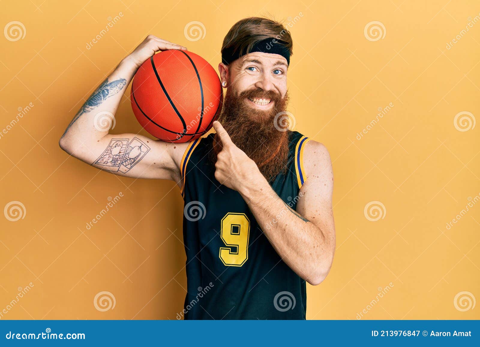 Redhead Man With Long Beard Wearing Basketball Uniform Holding Ball