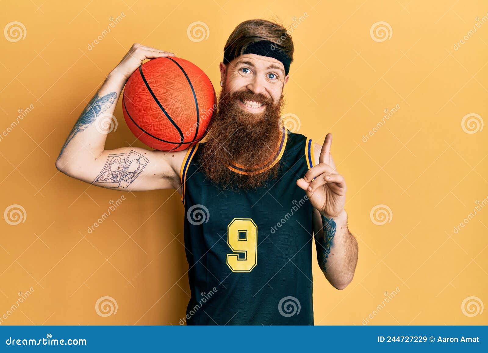 Redhead Man With Long Beard Wearing Basketball Uniform Holding Ball