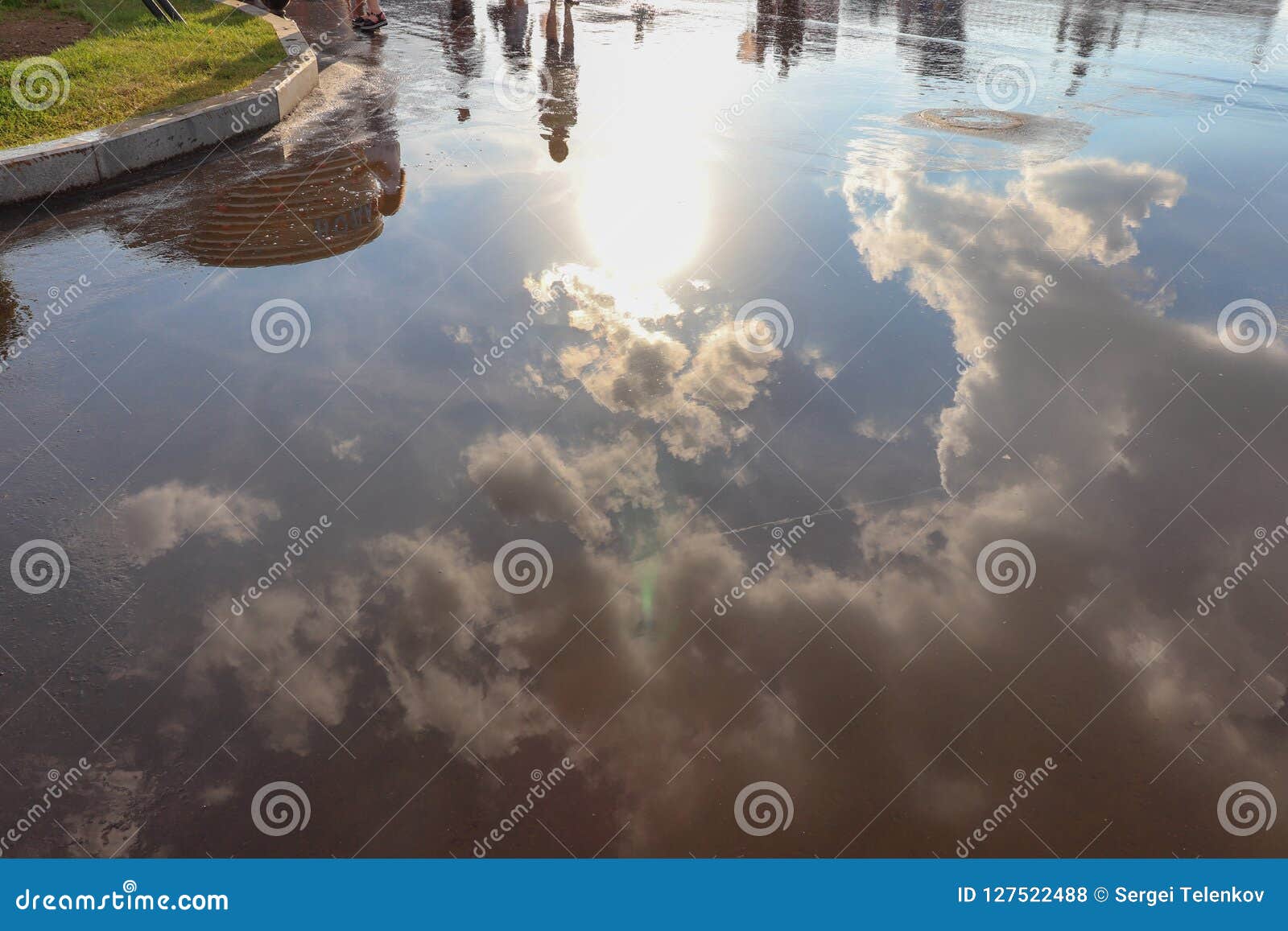 Reflection of the Sun and Blue Sky with Clouds in a Puddle. Stock Photo ...
