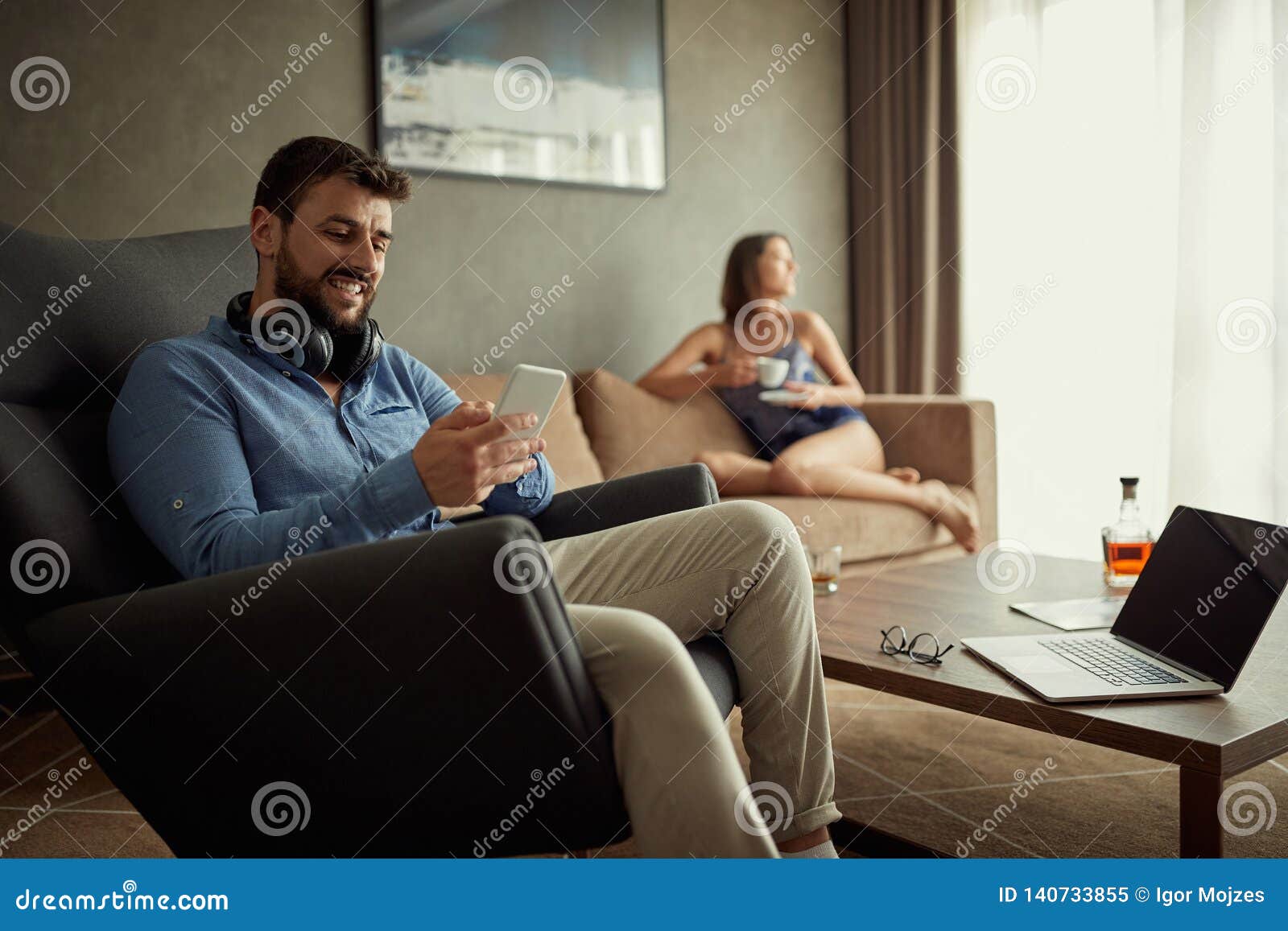 Relaxed Man Using Phone while Sitting on Sofa at His Modern Home Stock ...