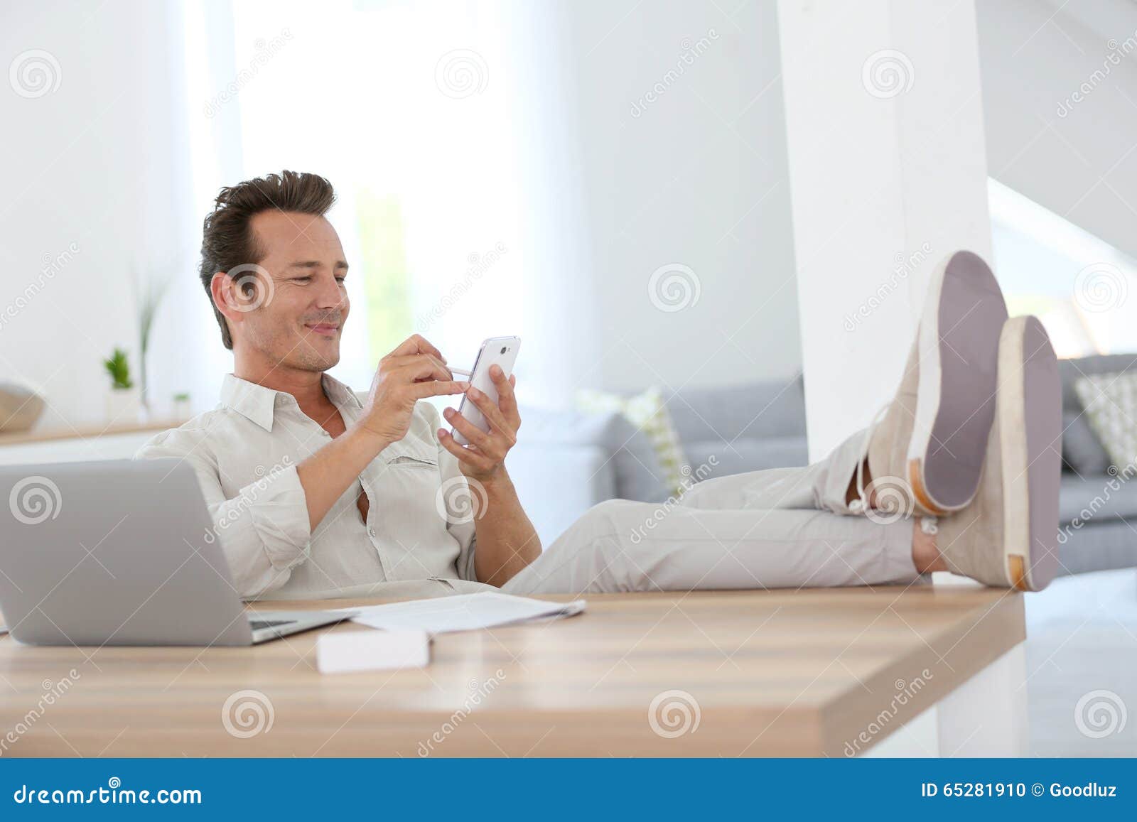 Relaxed Man Using Smartphone at Home with Feet on Table Stock Photo ...