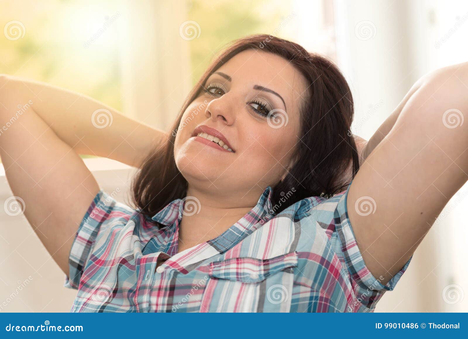 Relaxed Young Woman Smiling With Arms Behind The Head Light Effect