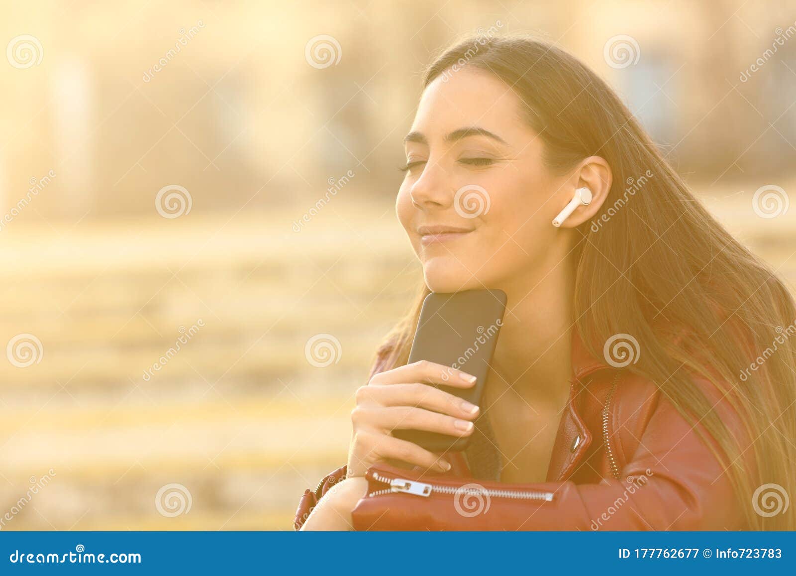 Relaxed Woman Wearing Earbuds Listens To Music On Phone Stock Image