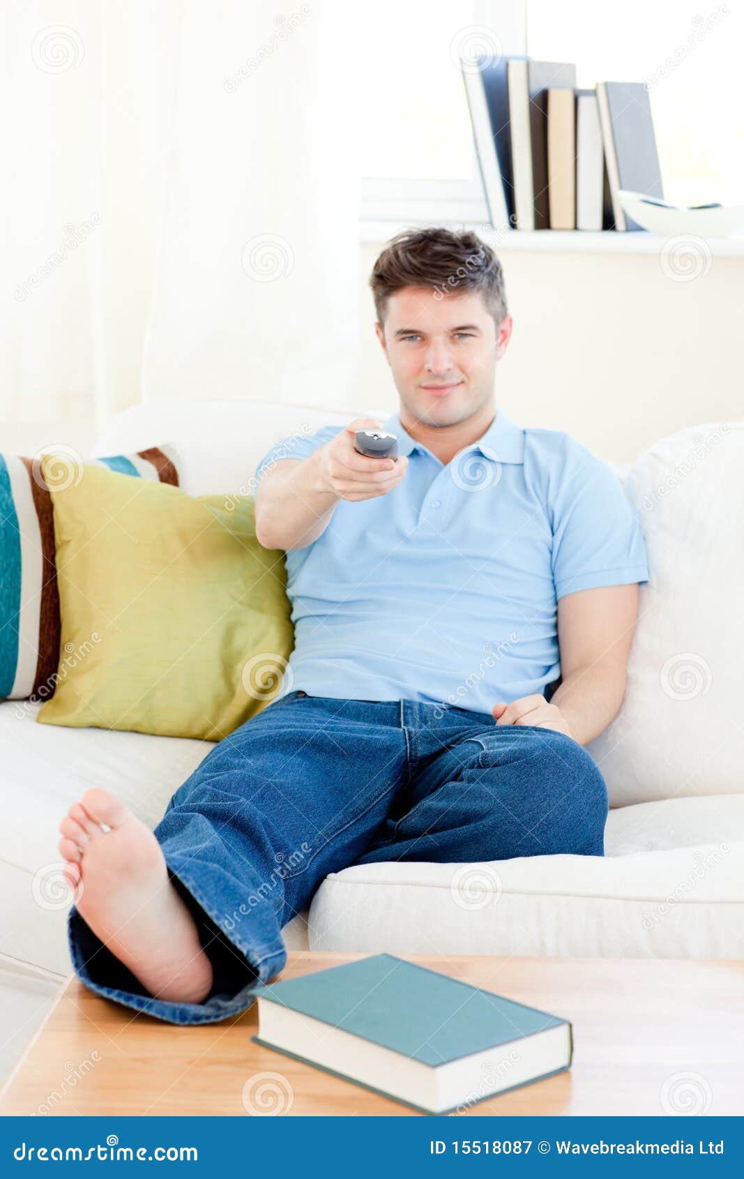 Relaxed Young Man Holding a Remote Sitting on Sofa Stock Image - Image ...