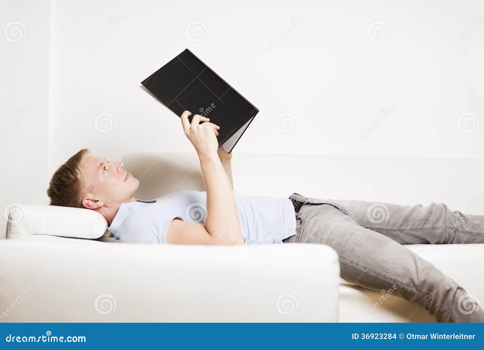 Relaxed Young Man Reading a Book and Lying on Sofa. Stock Photo - Image ...