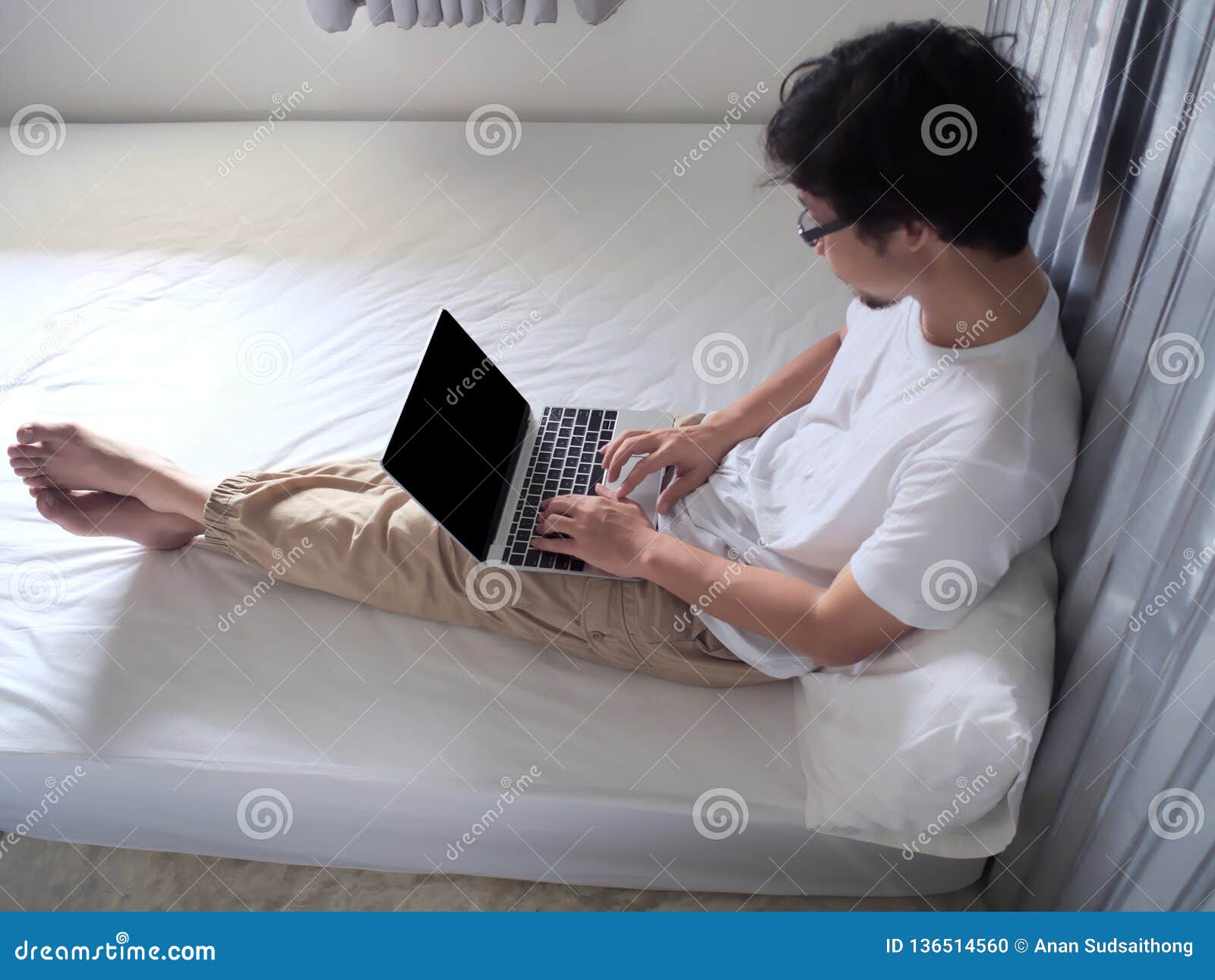 Relaxed Young Man Using Computer Laptop on the Bed in Bedroom. Internet ...