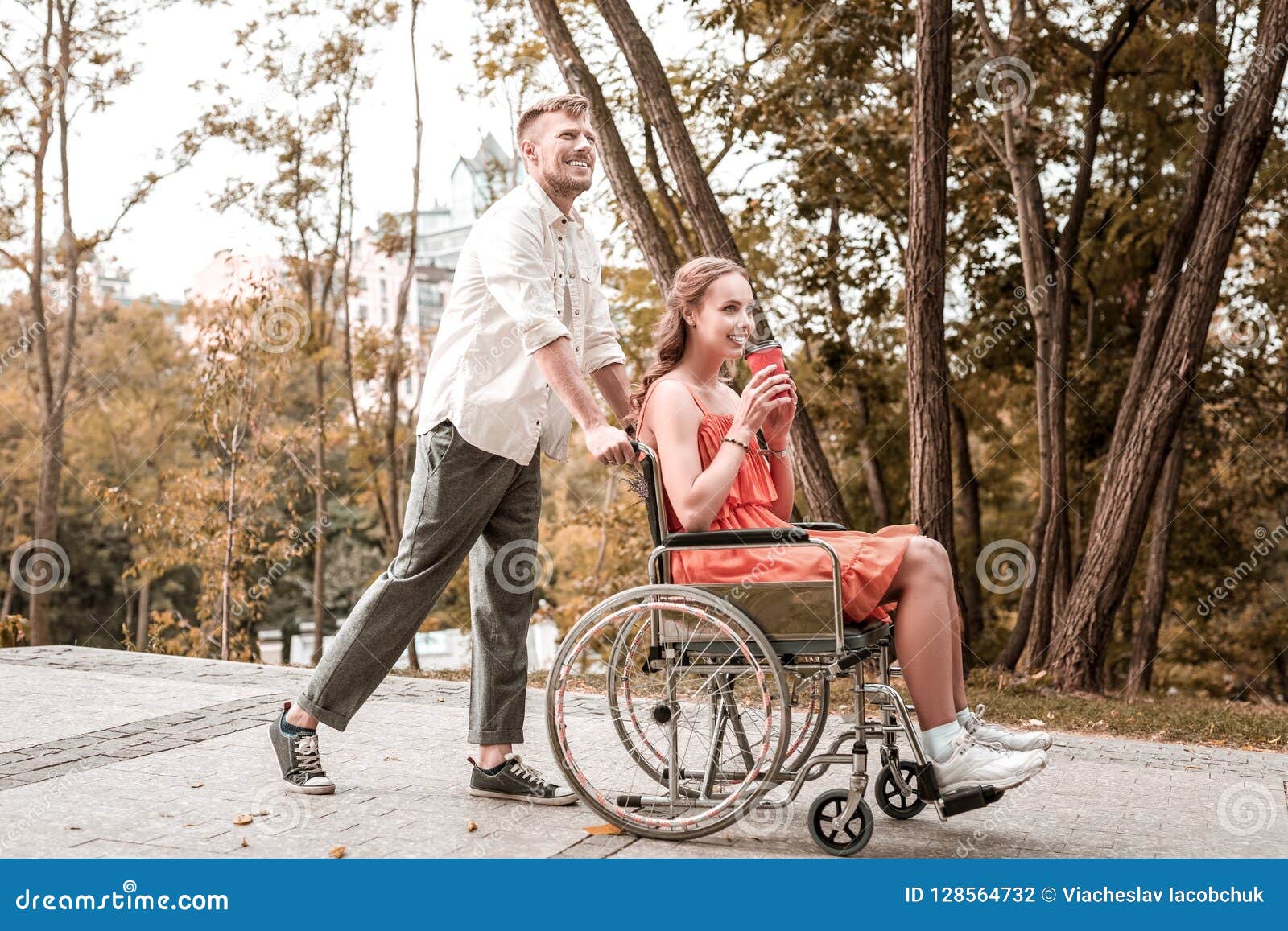 Happy Man Pushing the Wheelchair of His Girlfriend while Walking in the ... Happy Man Pushing the Wheelchair of His Girlfriend while Walking in the ...