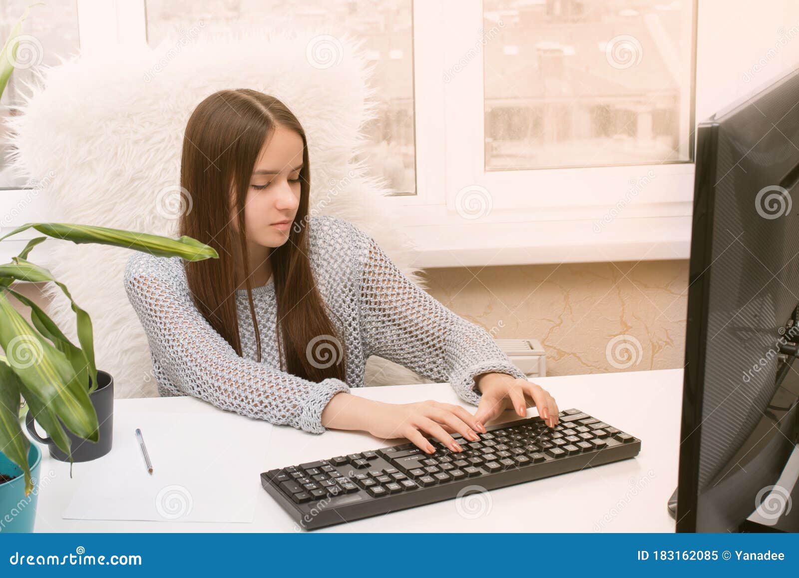 Remote Work. Young Girl Sits at a Table, Typing on a Computer, Smiling ...