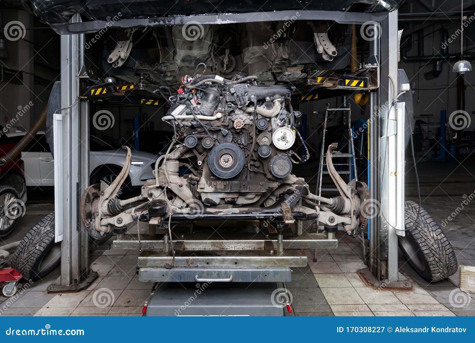 Replacement Used Engine on a Table Mounted Under Raised Car on Lift for ...