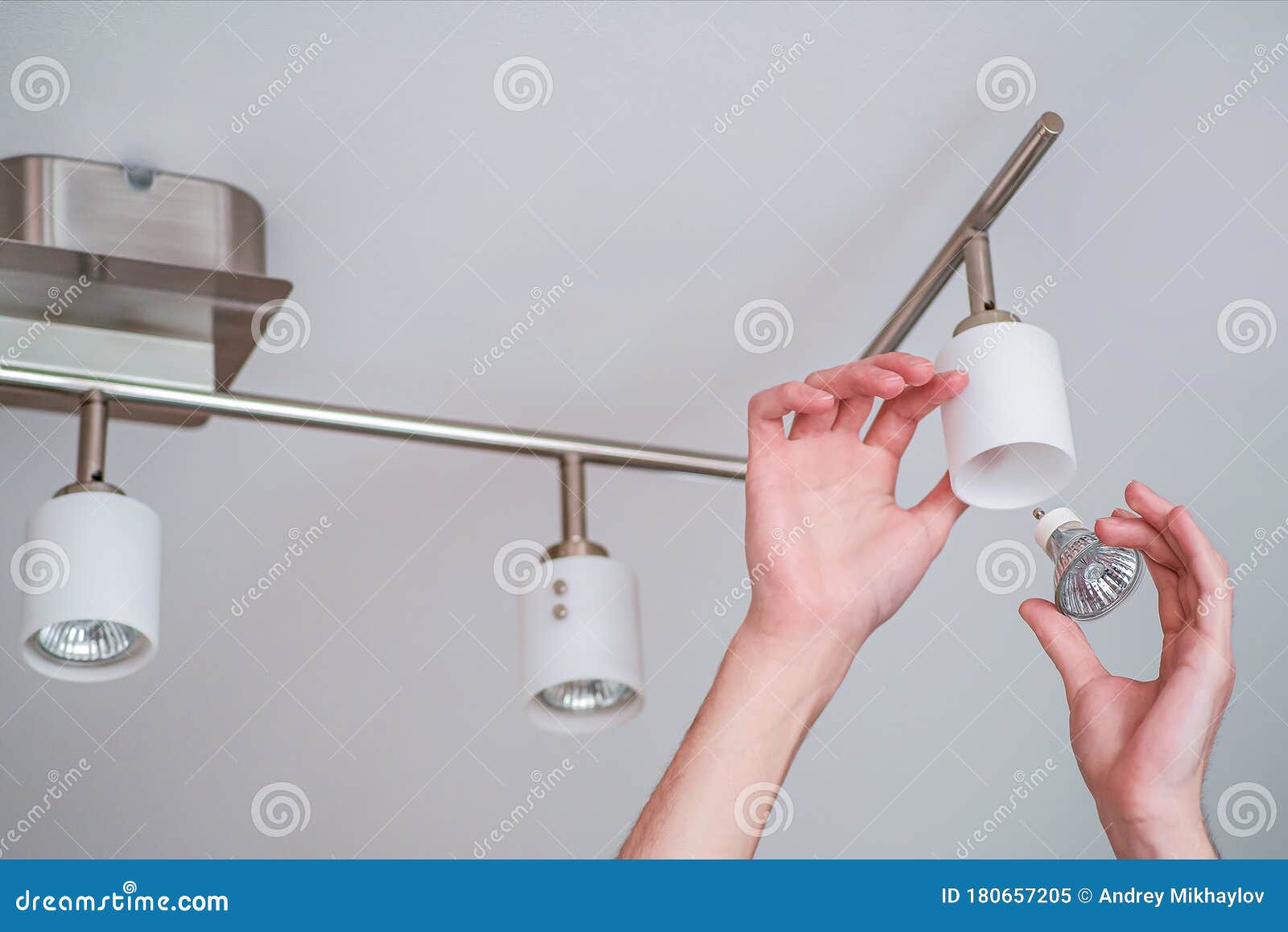 Replacing a Burned-out Halogen Lamp in the Soffit. the Man Holds the ...