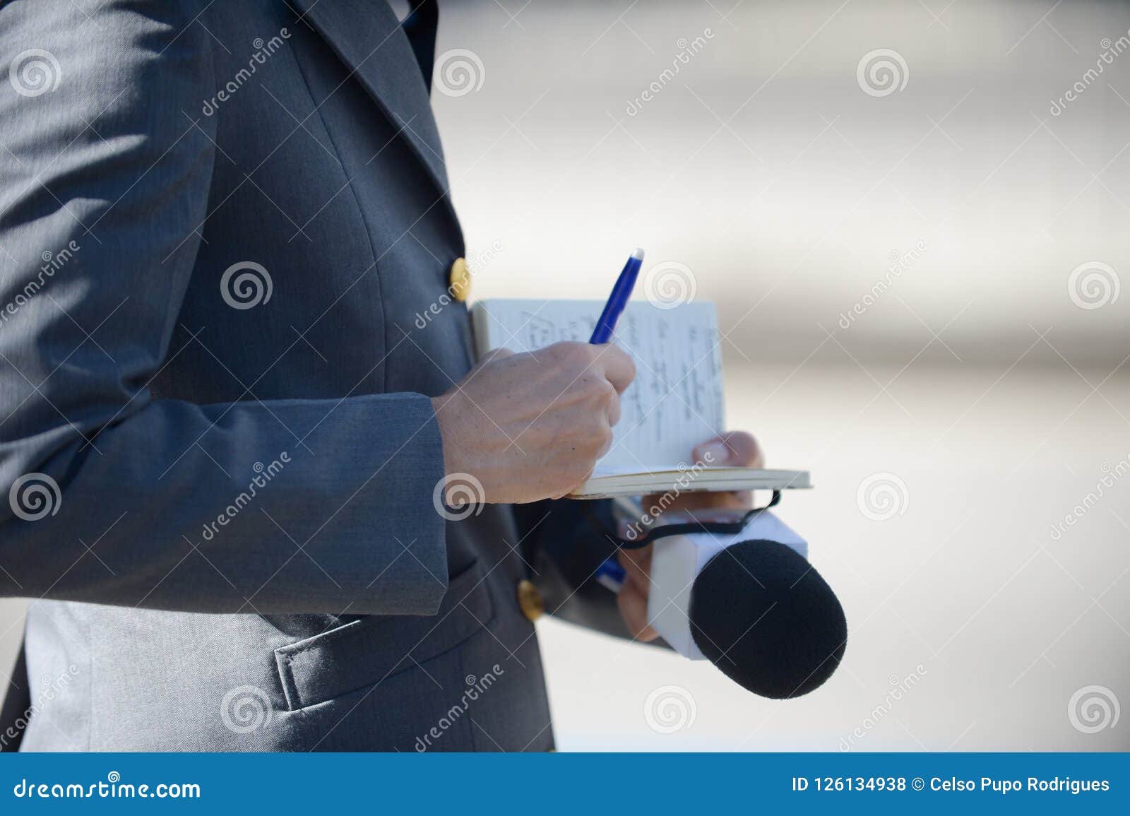 Reporter Writing His Notes in a Notebook and Holding the Microphone ...