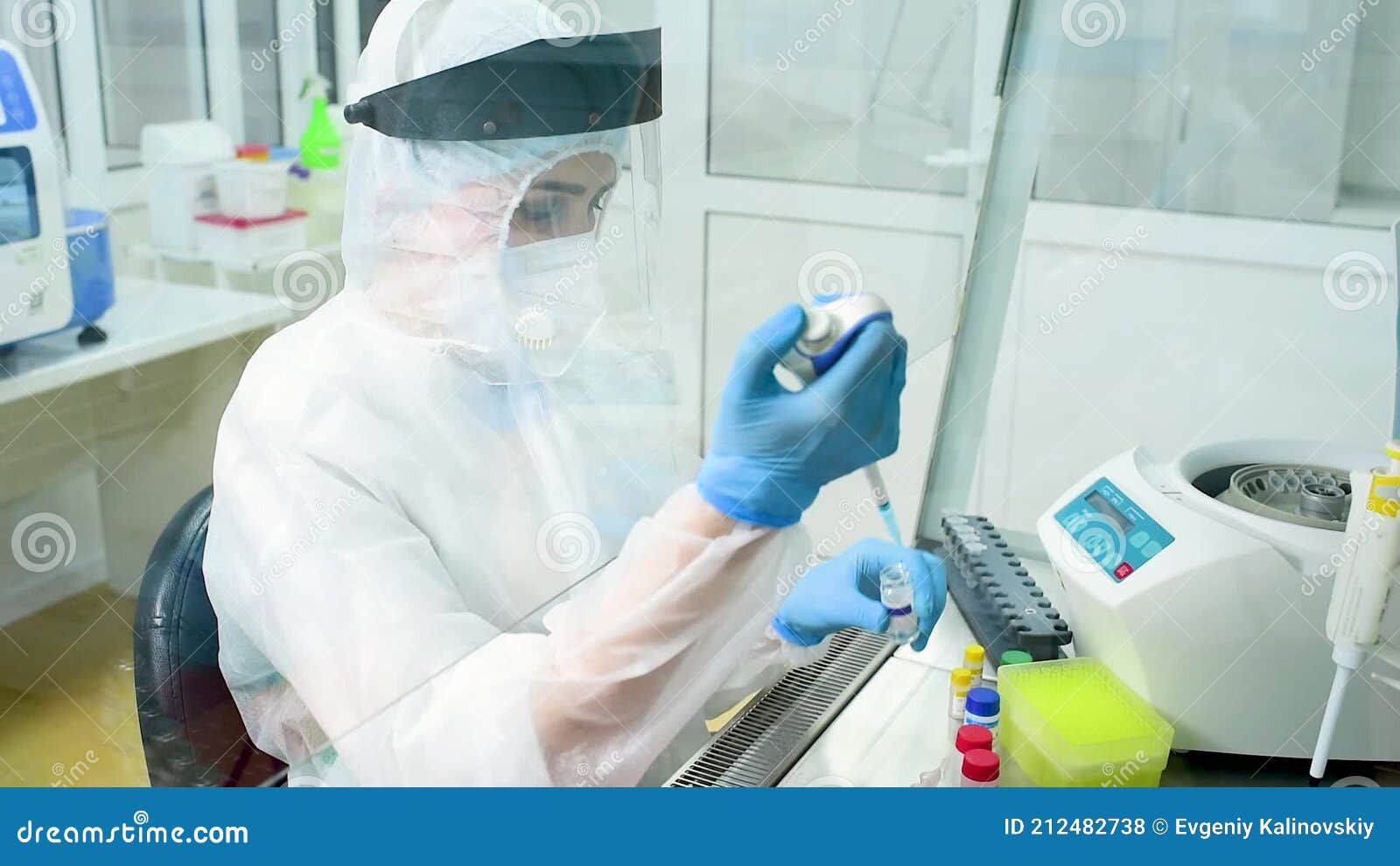 Researcher Microbiologist in a Protective Suit Puts on a Protective ...