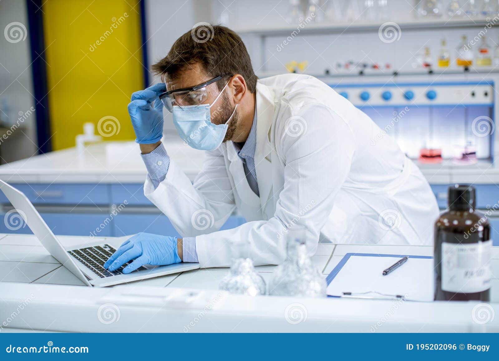 Researcher in White Lab Coat and Protective Mask Working Using Laptop ...