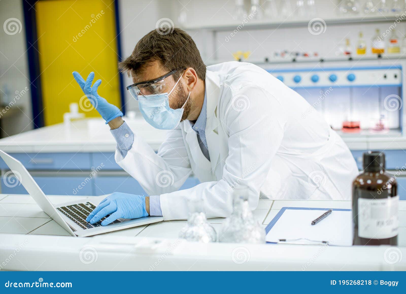 Researcher in White Lab Coat and Protective Mask Working Using Laptop ...