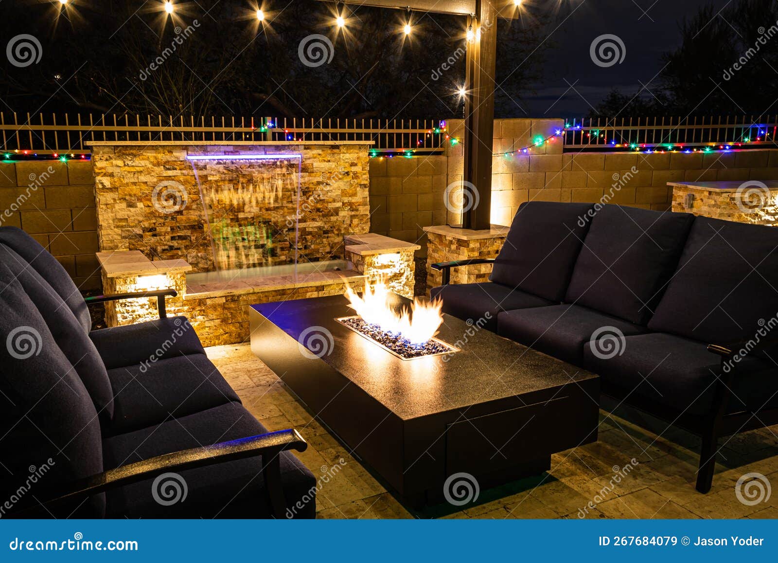 A Resort Style Backyard at Night with a Waterfall, Pergola, and a ...