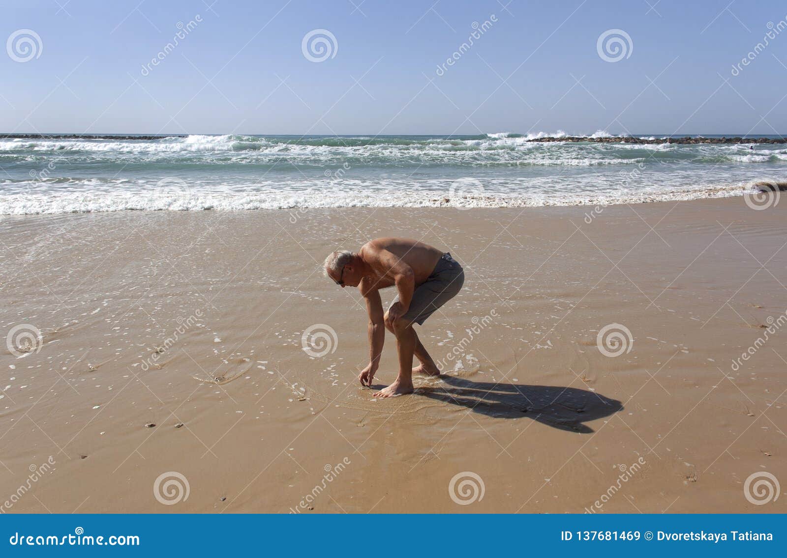 Resting Man Picks Up a Pebble from the Sand Stock Image - Image of ...