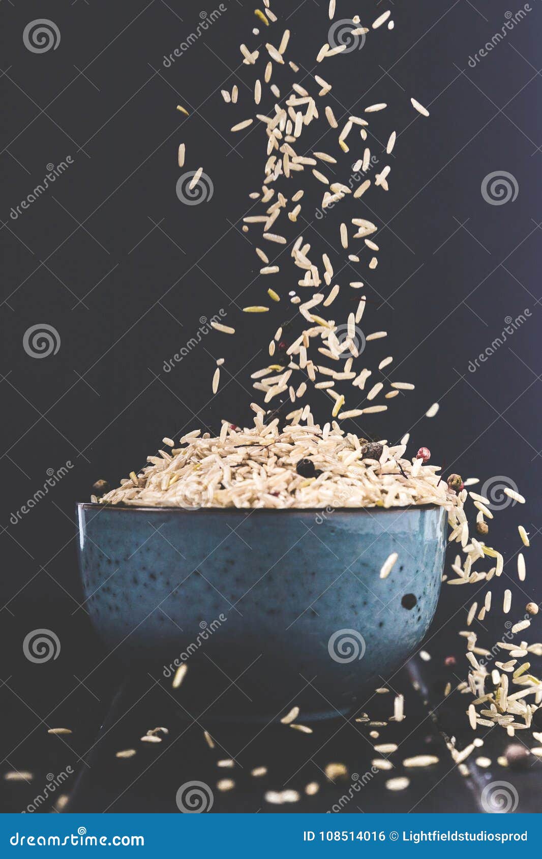 Rice Spilling into Bowl on Black Table Stock Photo - Image of ...