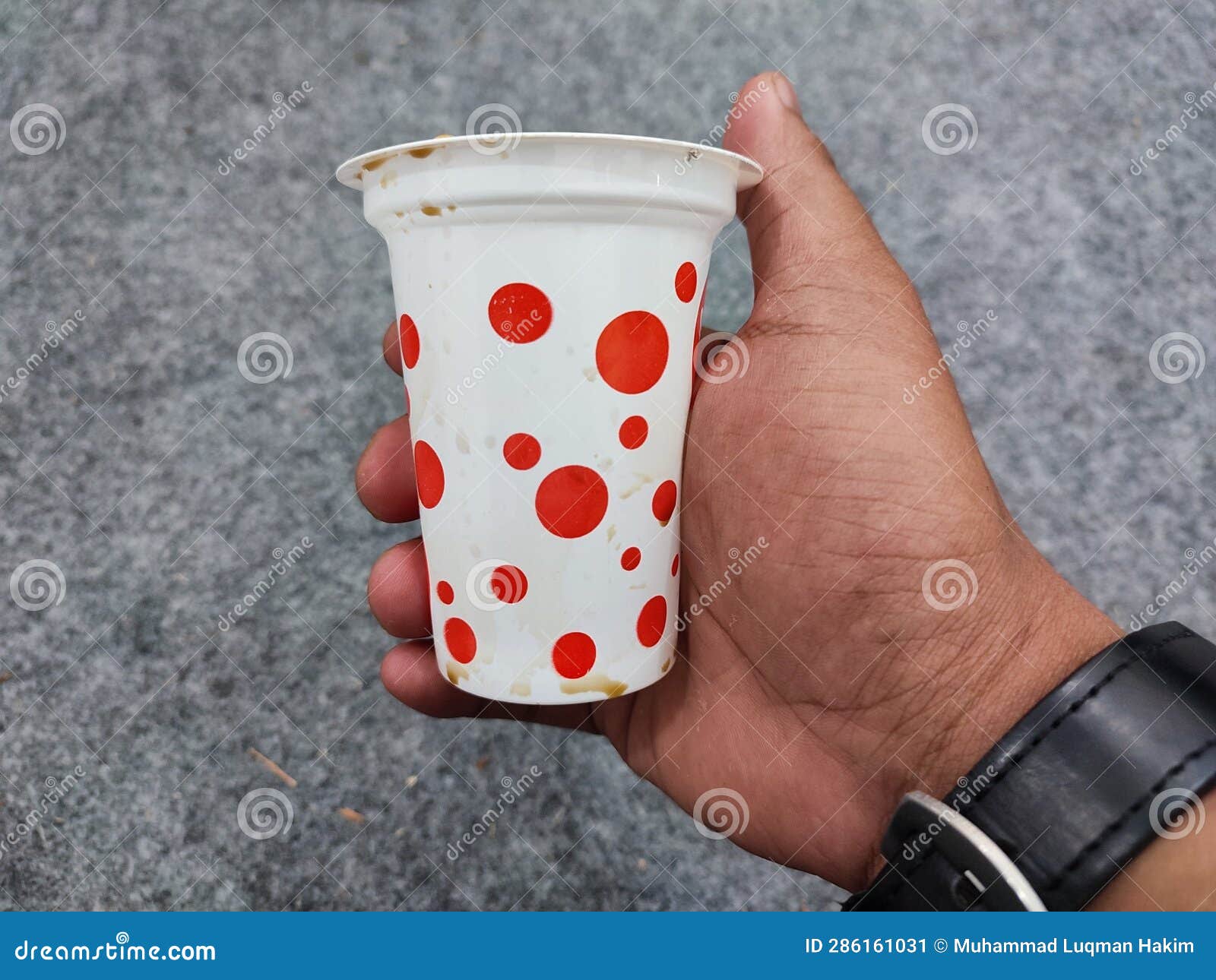 Right Hand Holding a Plastic Cup that Has a Red Pattern on White Stock ...