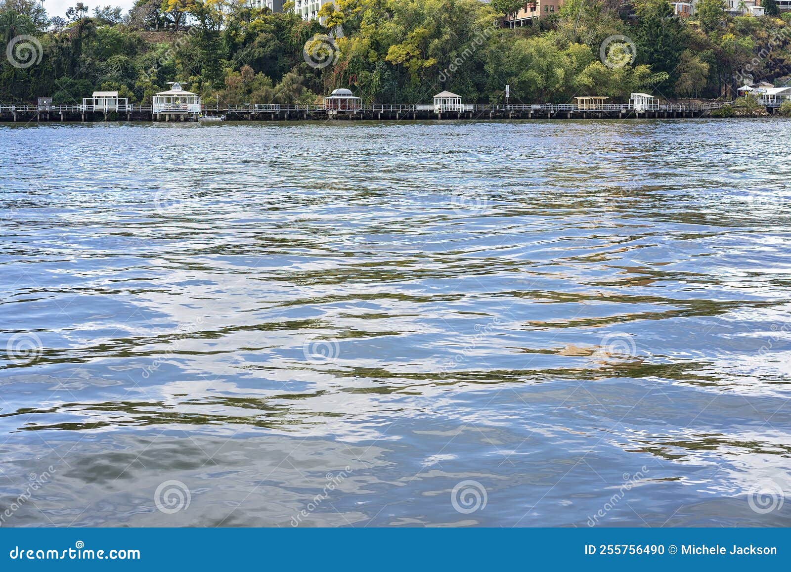River Water Foreground with Buildings and Boardwalk Background Stock ...