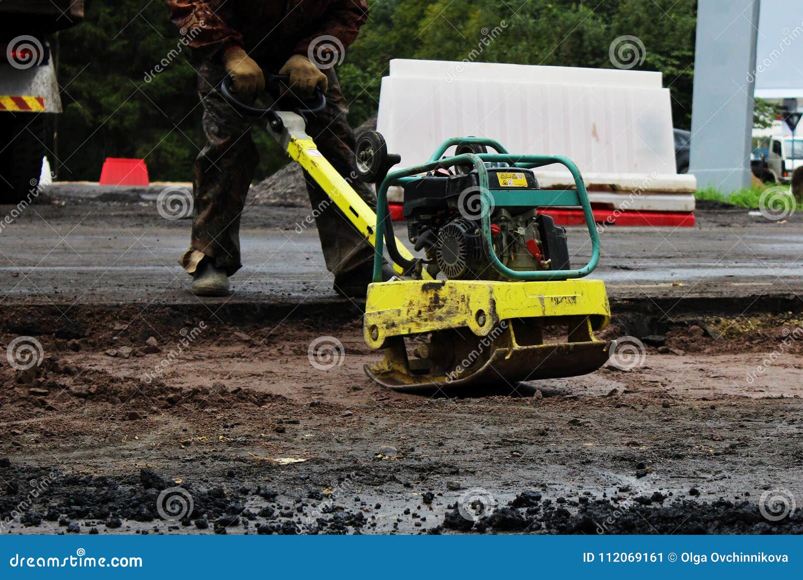 A Worker Compacts Soil Or Sand With A Vibrating Plate In A Trench At A ...