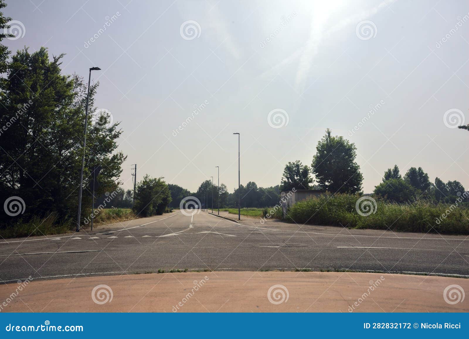 Road with an Empty Roundabout Bordered by Plants on a Sunny Day in the ...