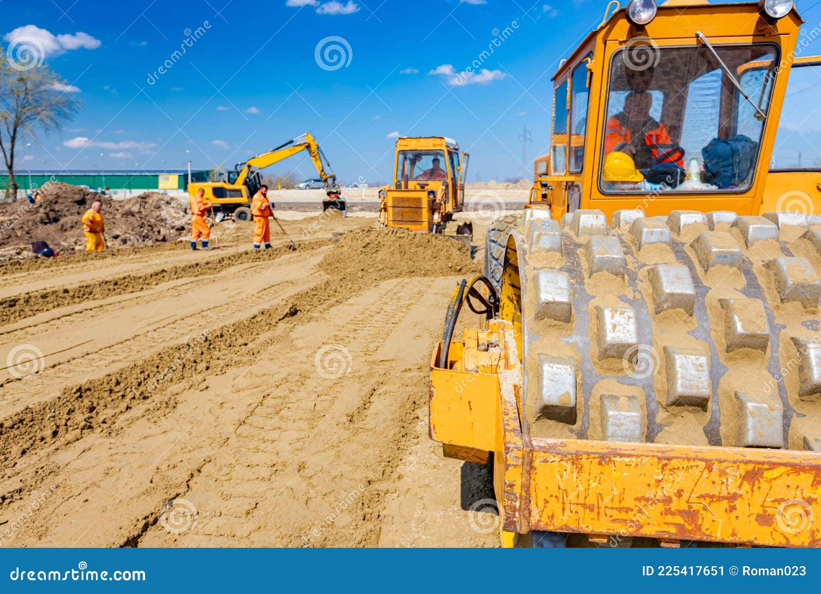 Road Roller with Spikes and Earthmover are Working at Construction Site ...