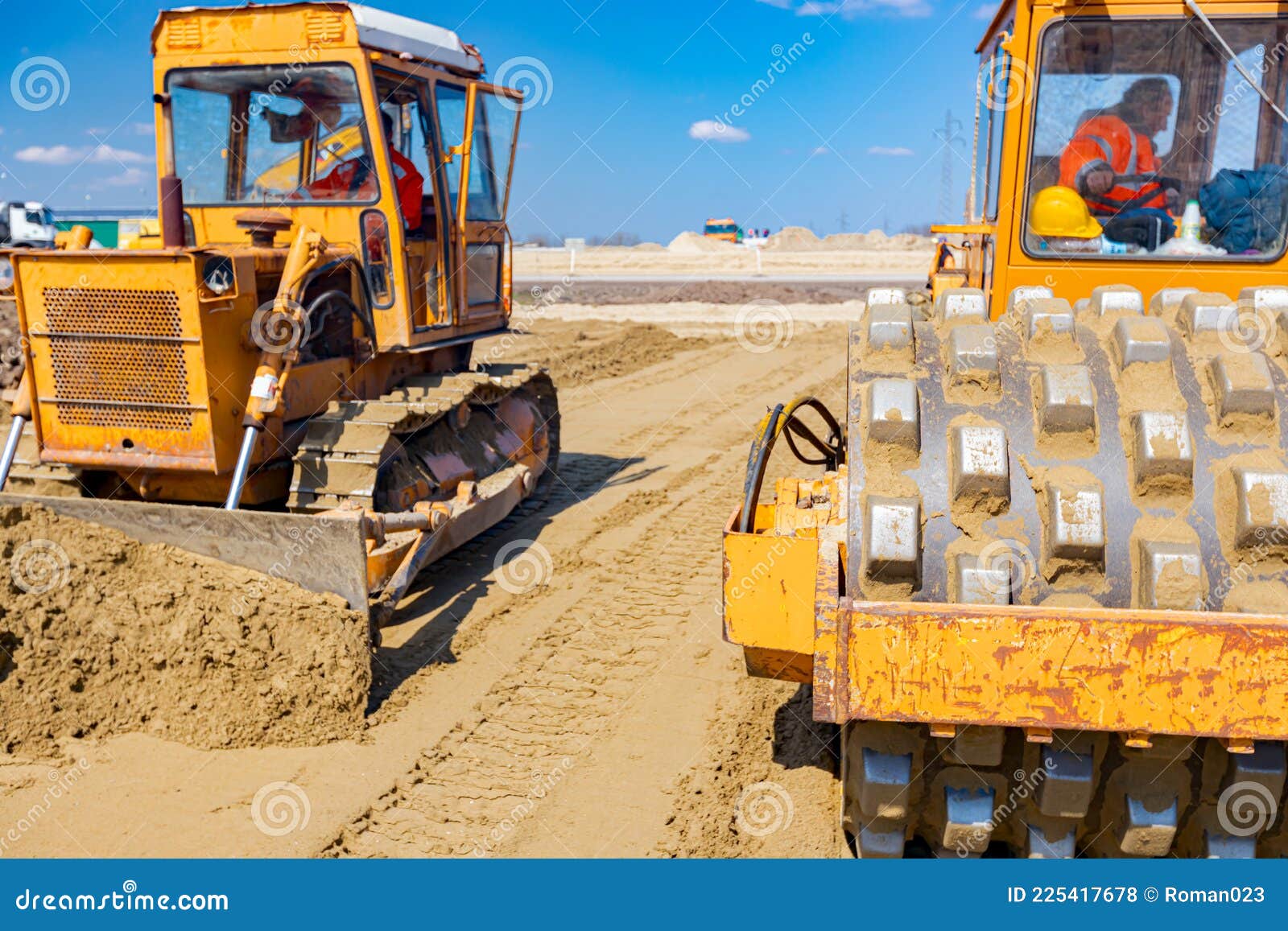 Road Roller with Spikes and Earthmover are Working at Construction Site ...