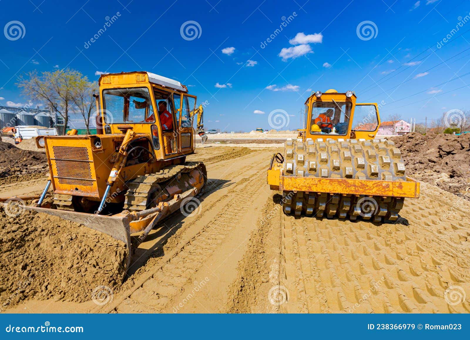 Road Roller with Spikes and Earthmover are Working at Construction Site ...
