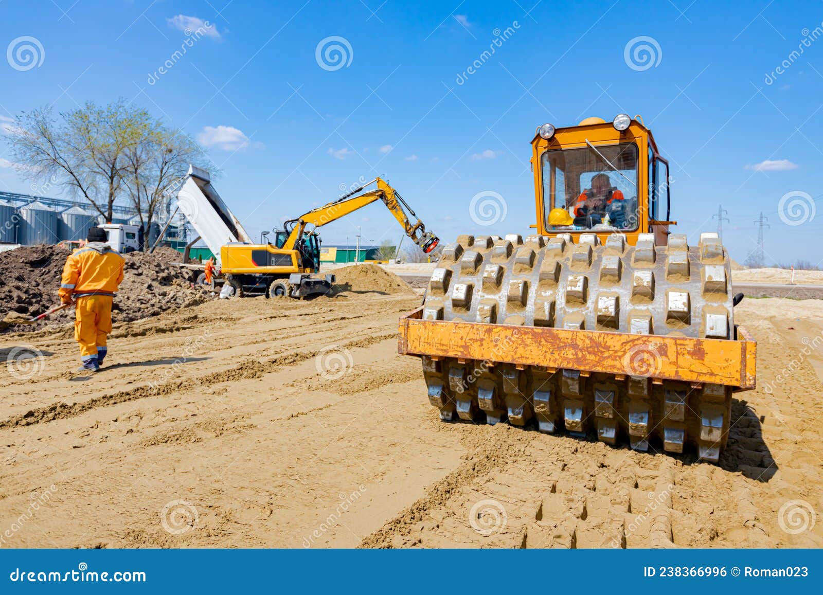 Road Roller with Spikes and Earthmover are Working at Construction Site ...