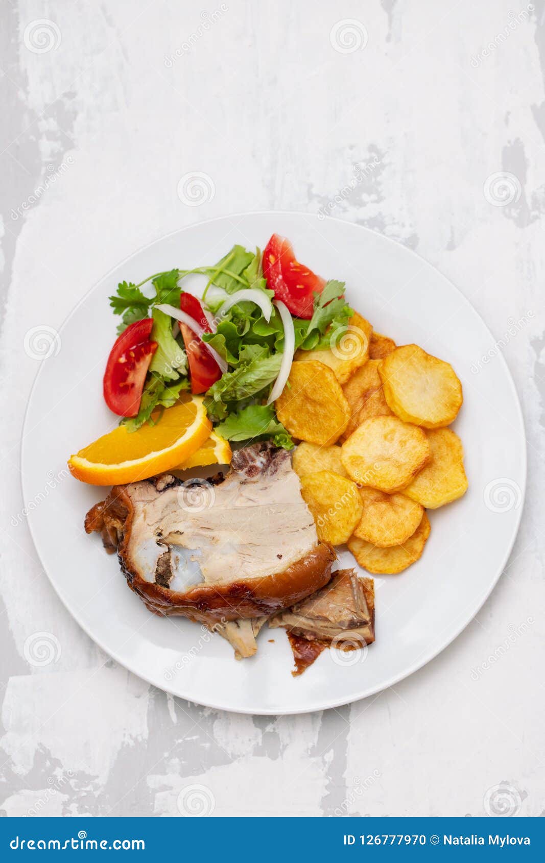 Roasted Piglet with Potato Chips and Orange on White Plate Stock Photo ...