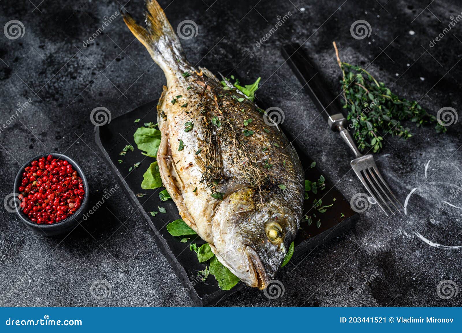 Roasted Sea Bream Fish with Herbs on a Cutting Board. Black Background ...