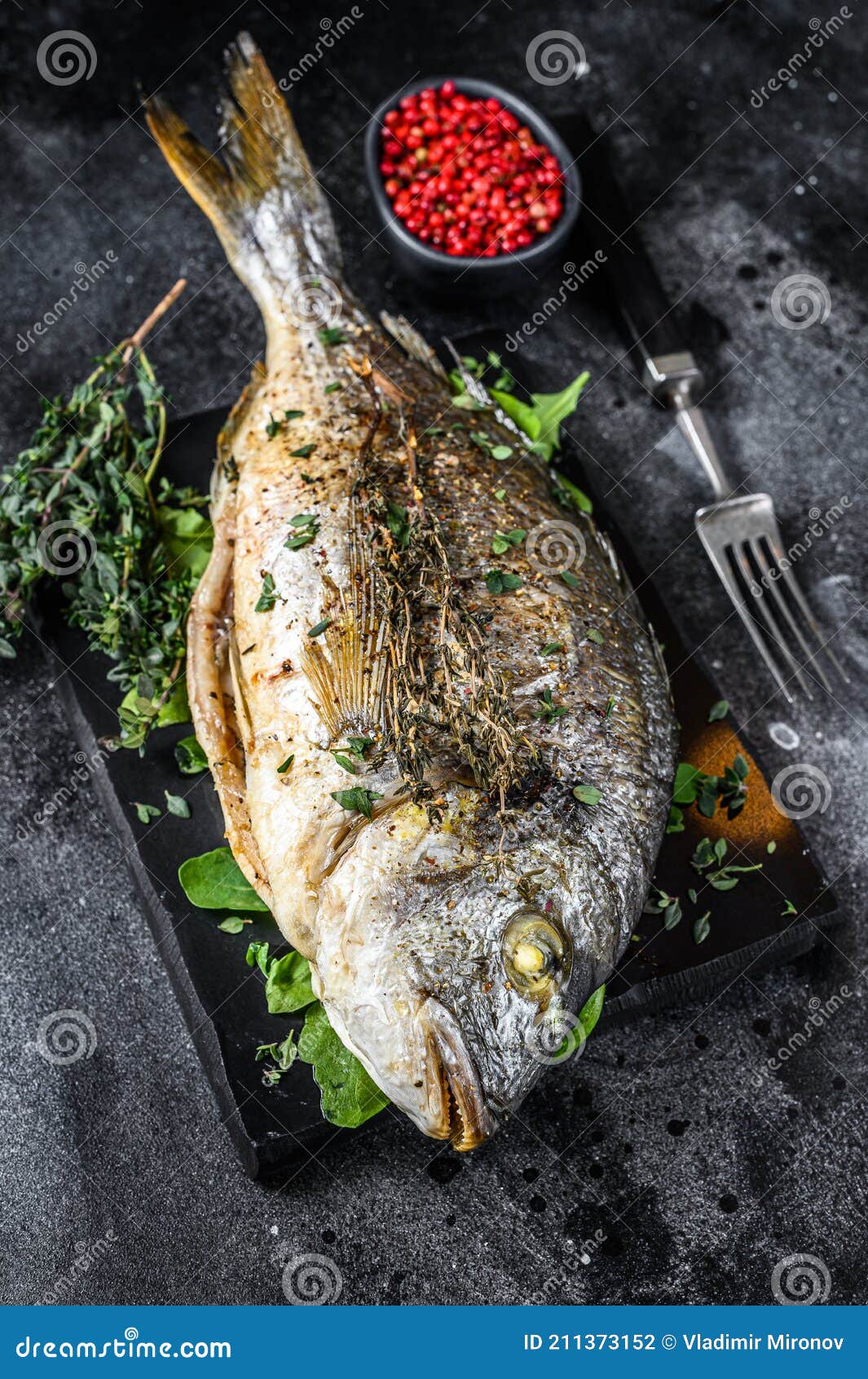 Roasted Sea Bream Fish with Herbs on a Cutting Board. Black Background ...