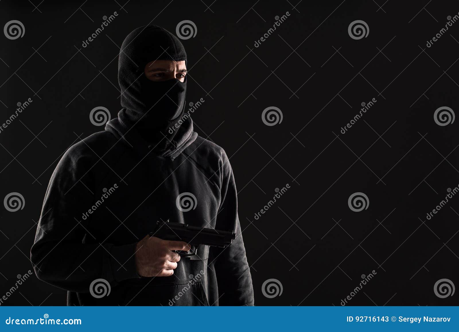 The Robber in a Mask with a Gun Pointed To the Side on a Black ...
