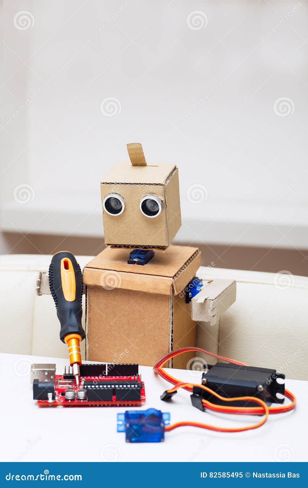 The Robot Holds a Screwdriver and Solder the Red Chip on the Table ...