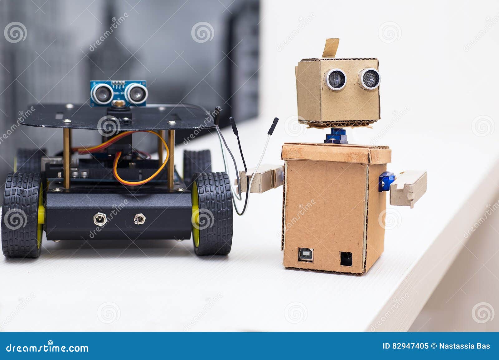 Robot Keeps Wires and Stands Next To the Other Robot on a White Table ...