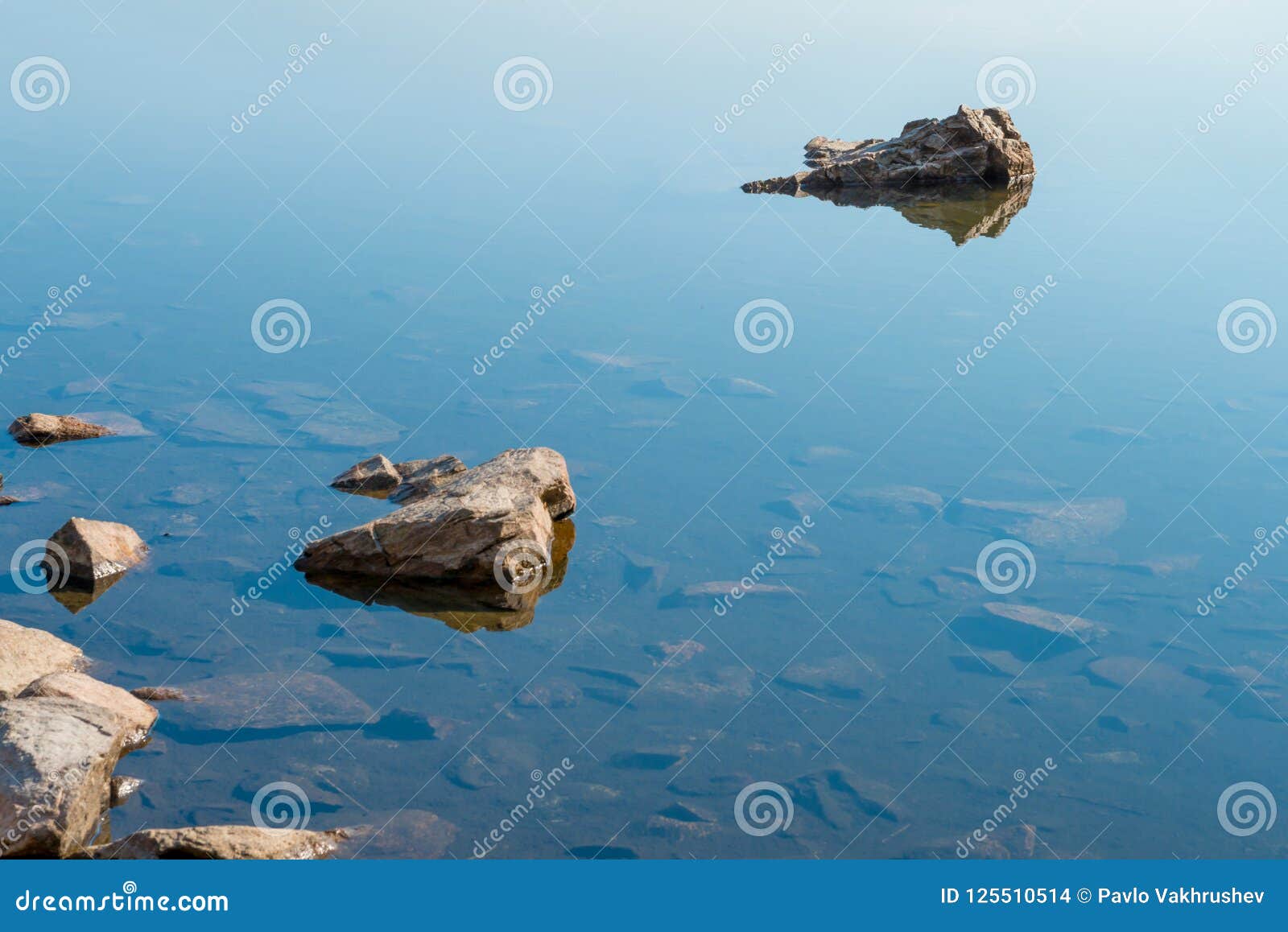 Rocks in blue calm water stock photo. Image of reflection - 125510514