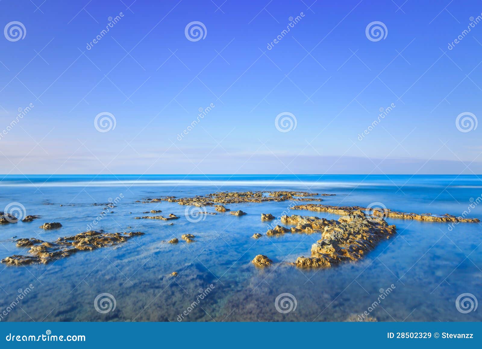 Rocks in a Blue Ocean Under Clear Sky on Sunrise. Stock Image - Image ...