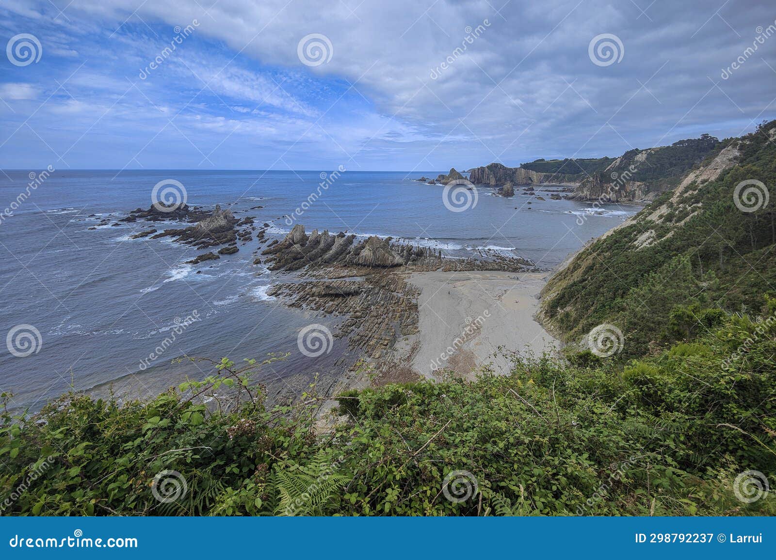 A Rocky Beach Cove with Lush Greenery on the Cliffs Under a Beautiful ...