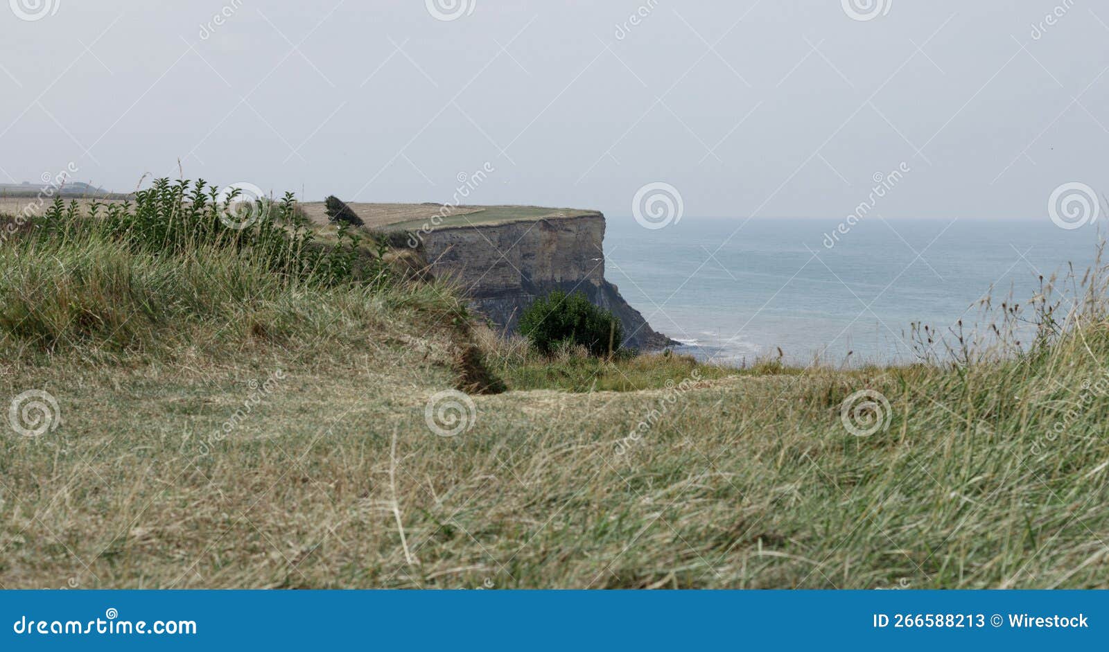 Rocky Cliff with Grass on the Foreground Against a Hazy Horizon Stock ...