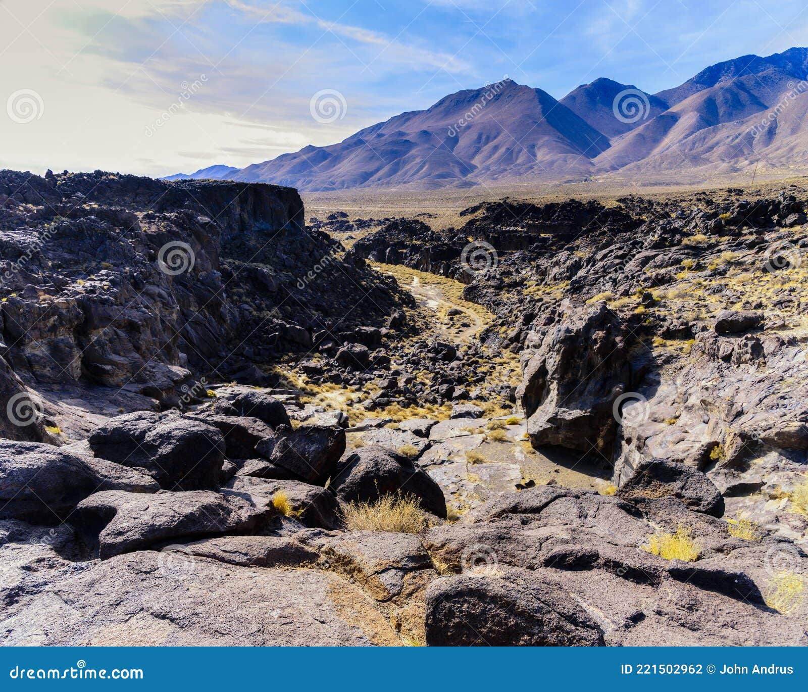 Rocky Cliffs with Dry Riverbed Below and Mountains Beyond Stock Photo ...