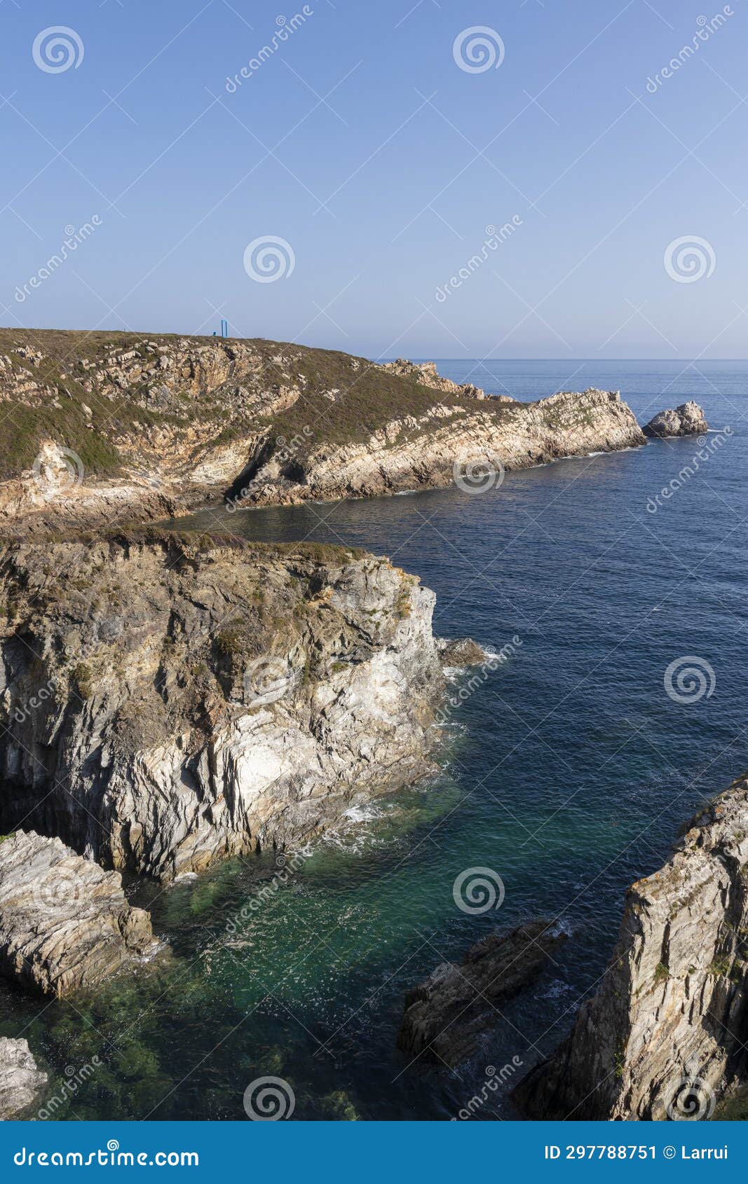 A Rocky Coastline with Clear Blue Water and a Small Lighthouse in the ...