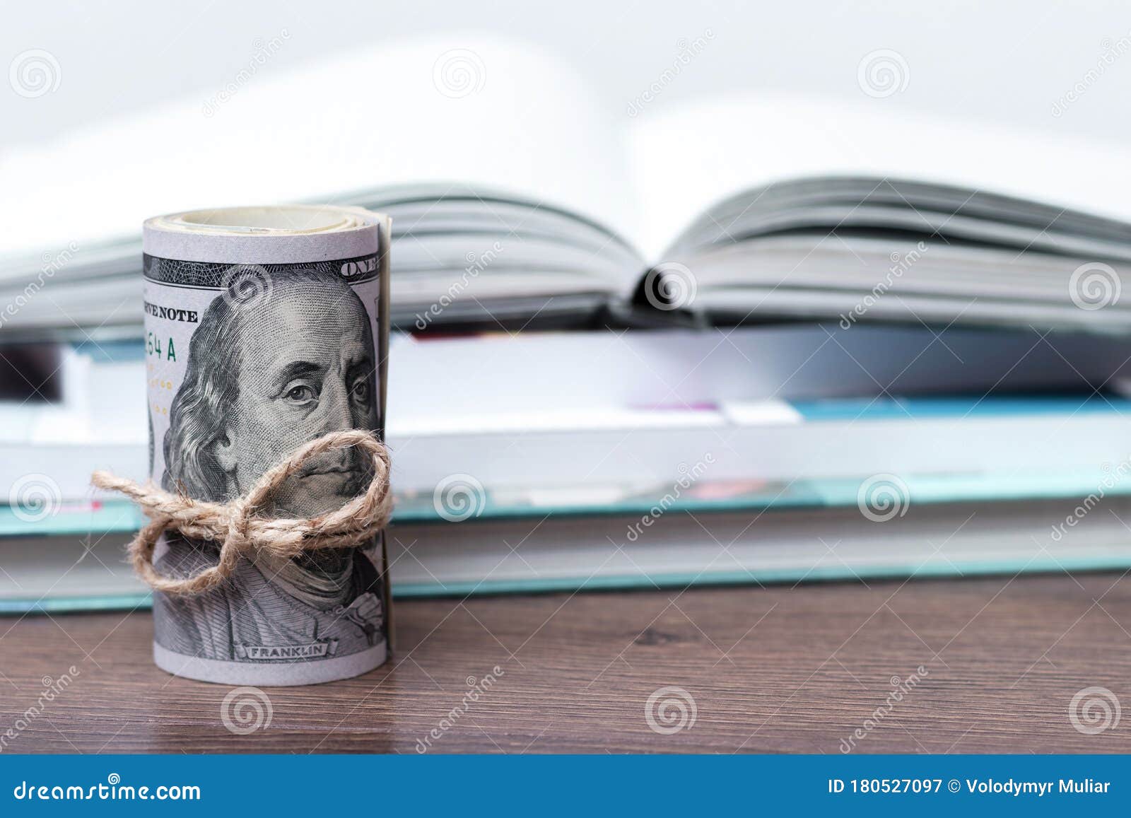 Roll of Money on a Background of Books, Paying for Literary Work Stock ...
