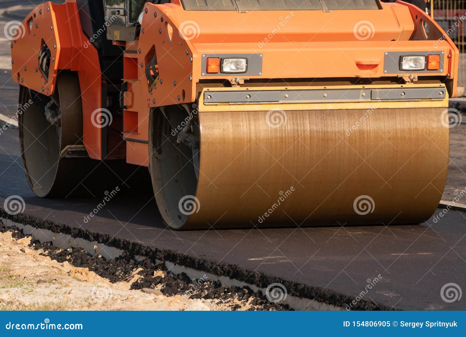 Roller Compacts Asphalt on the Road during the Construction of the Road ...