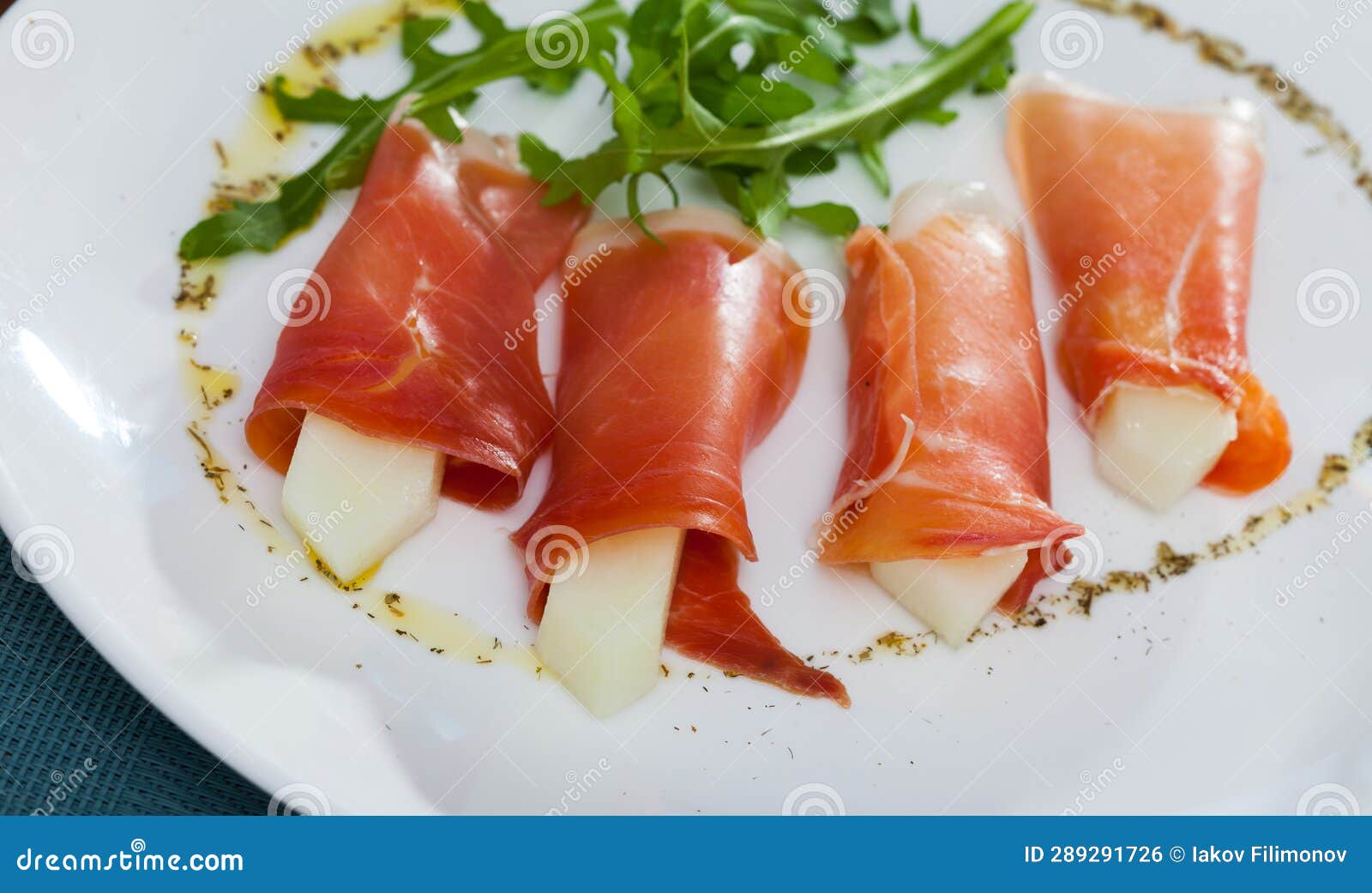 Rolls of Iberian Jamon Stuffed with Melon at Plate with Arugula Stock ...