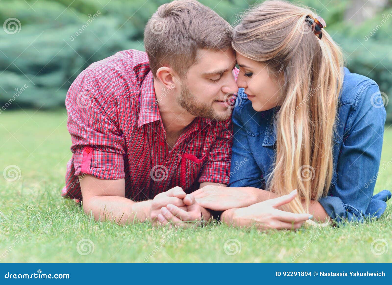 Romantic Couple Lying On Grass In The Park And Look Into Each Other`s