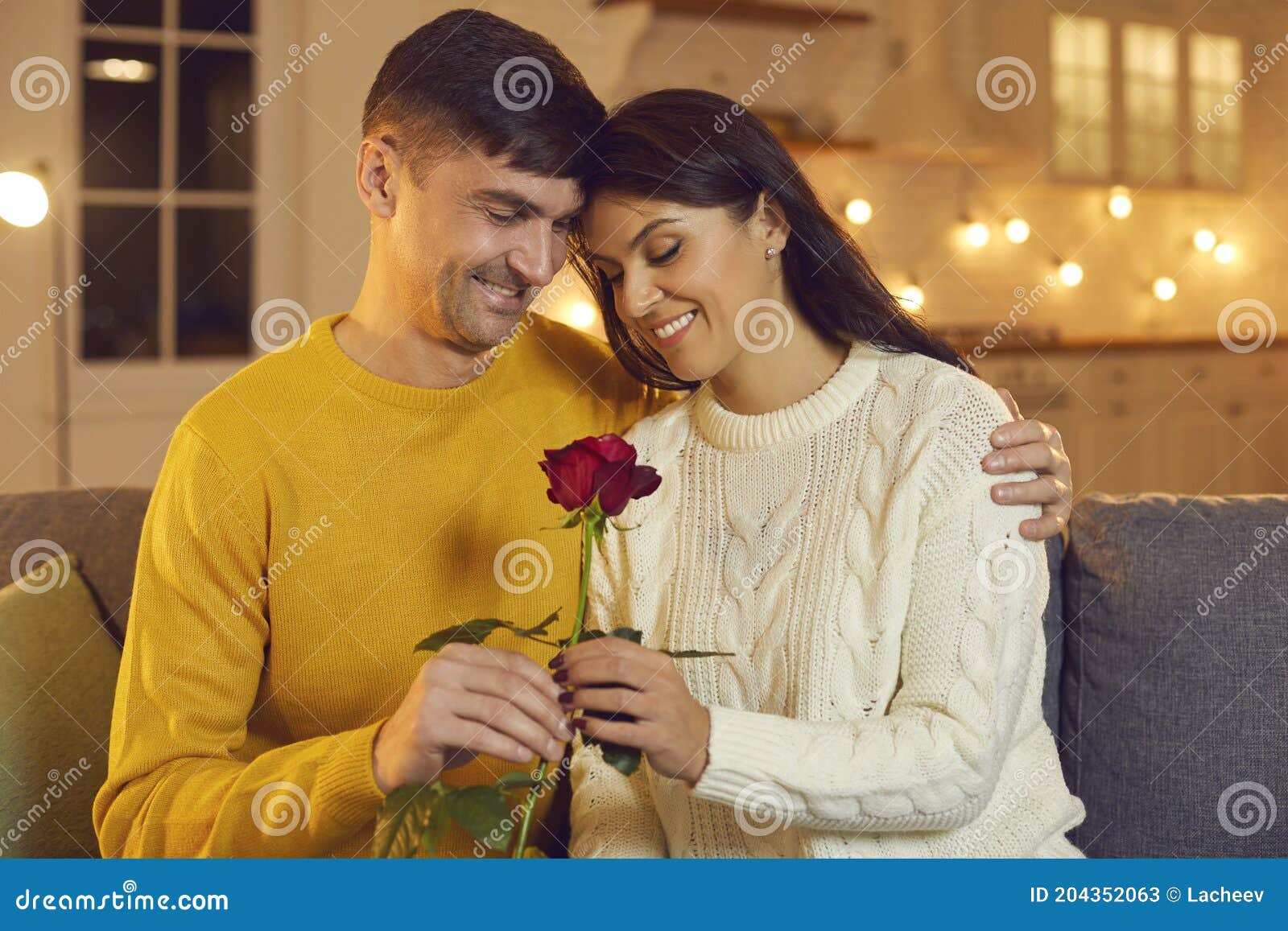Husband Tenderly Embraces His Wife Giving Her A Red Rose Which Is A