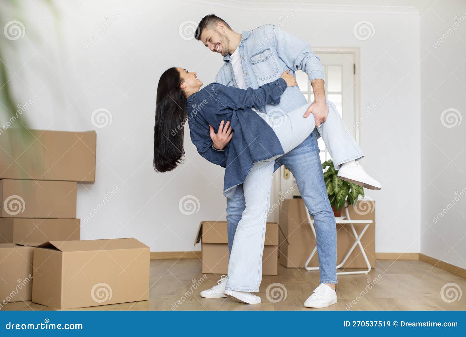 Romantic Young Couple Dancing In Room With Cardboard Boxes On Moving