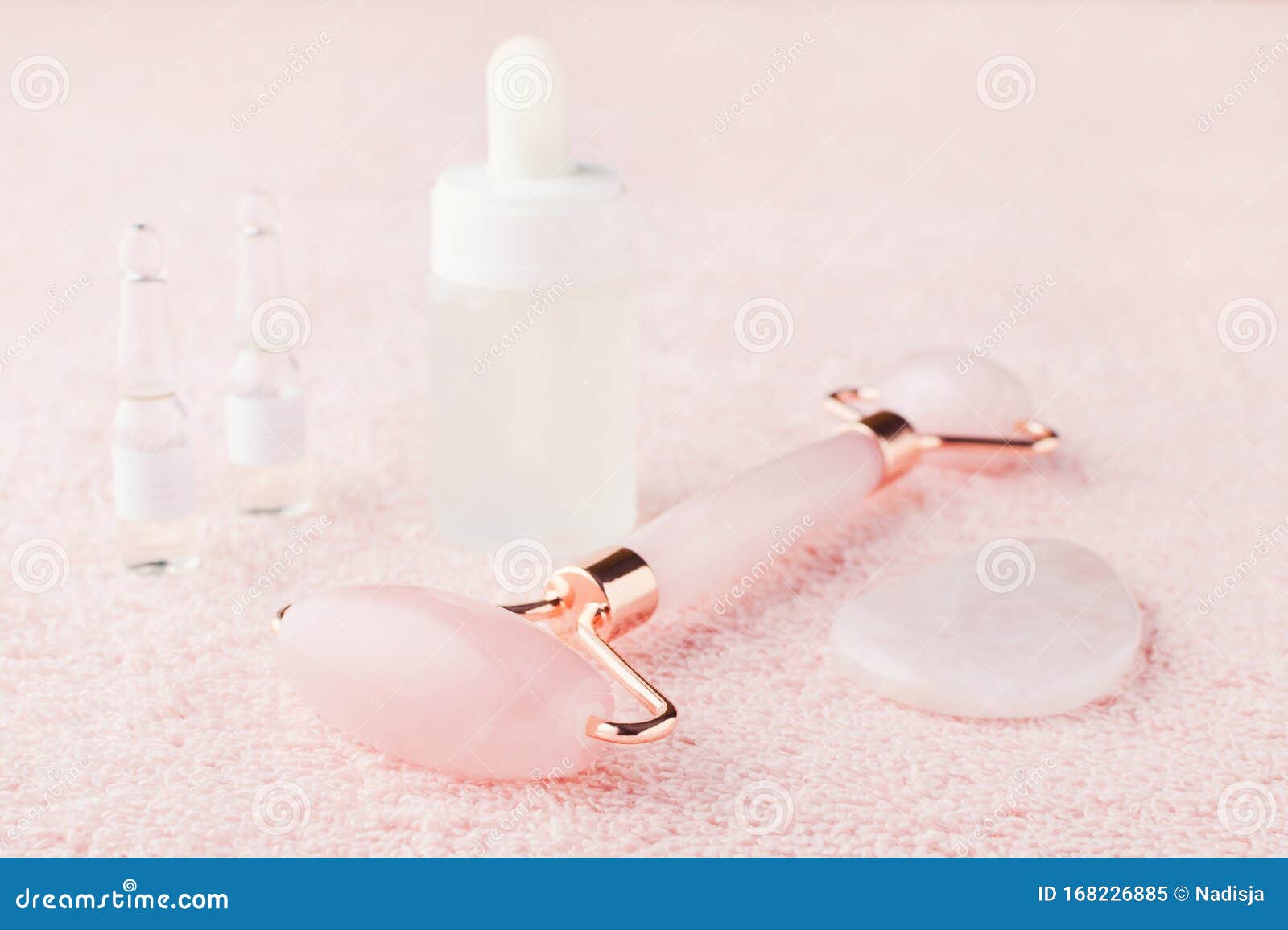 Rose Quartz Facial Roller Gua Sha Massage Stone And Face Serum On Pink